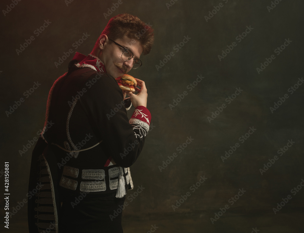 Young man in suit as royal person isolated on dark green background ...