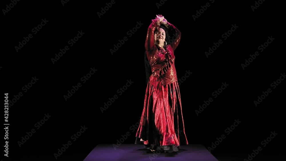 A barefoot gypsy woman with long hair in a red suit dances incendiaryly ...