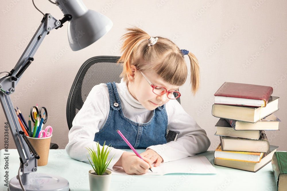 Fotografia do Stock: A little girl writes in a notebook. Child with two ...