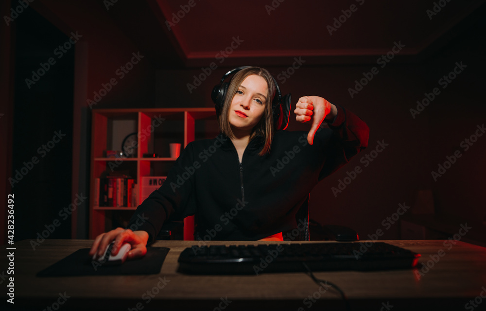 Dissatisfied girl gamer in headphones sits at night at the computer at ...