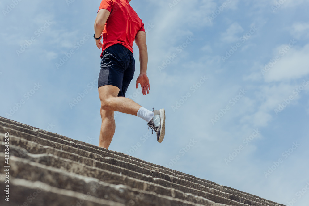 Back view photo from below of a male athlete's body running on the ...