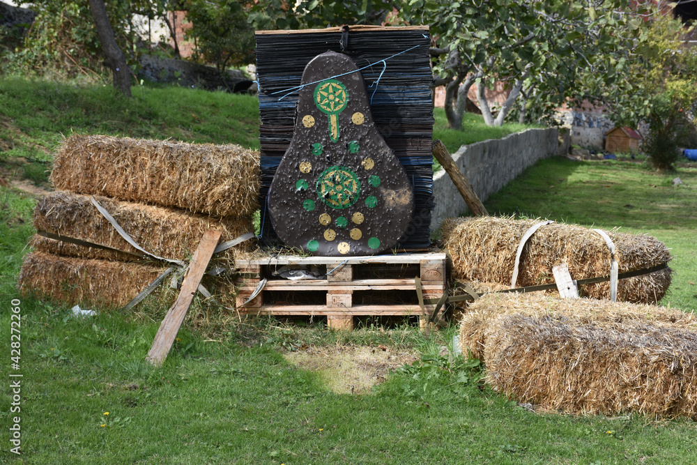 Traditional arrow target board with arrows stuck on it near haystack on ...