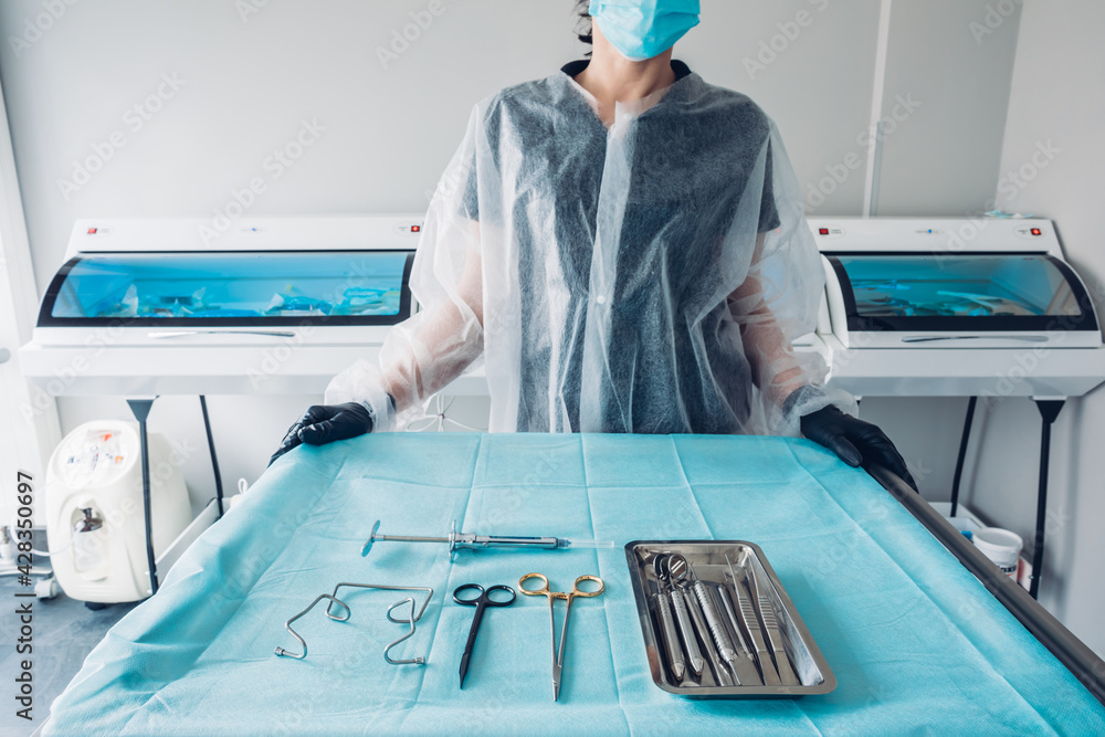 Nurse preparing table with set of sterile surgical instruments for a ...
