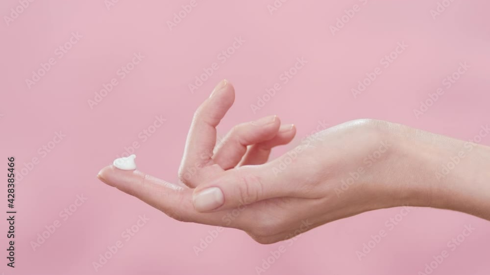 Female skincare model lifts her hand with a blob of cream on forefinger ...