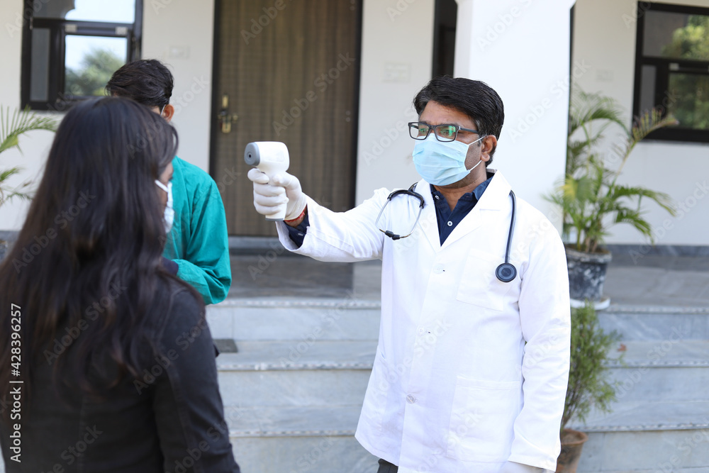 Young doctor measuring the body temperature of his patient with a ...