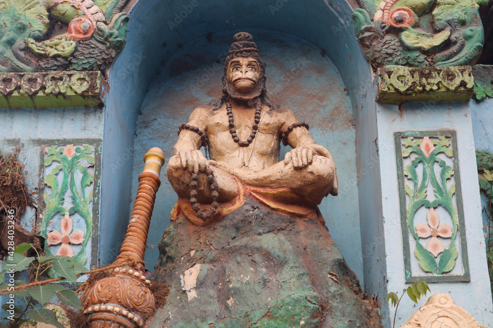 An old sculpture of Hanuman sitting in a lotus posture with rosary ...
