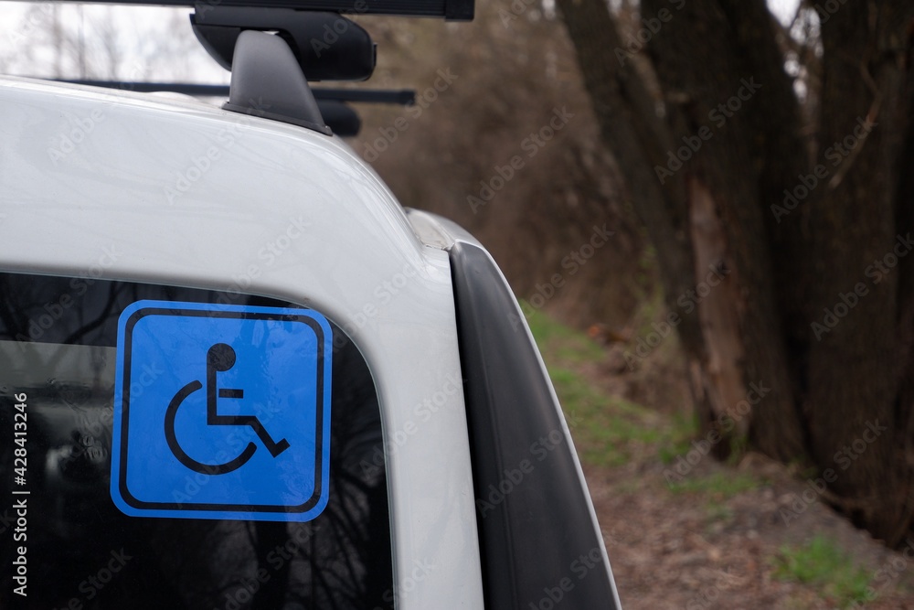 Disabled sign on a car. Blue sticker on the rear window of a white car ...