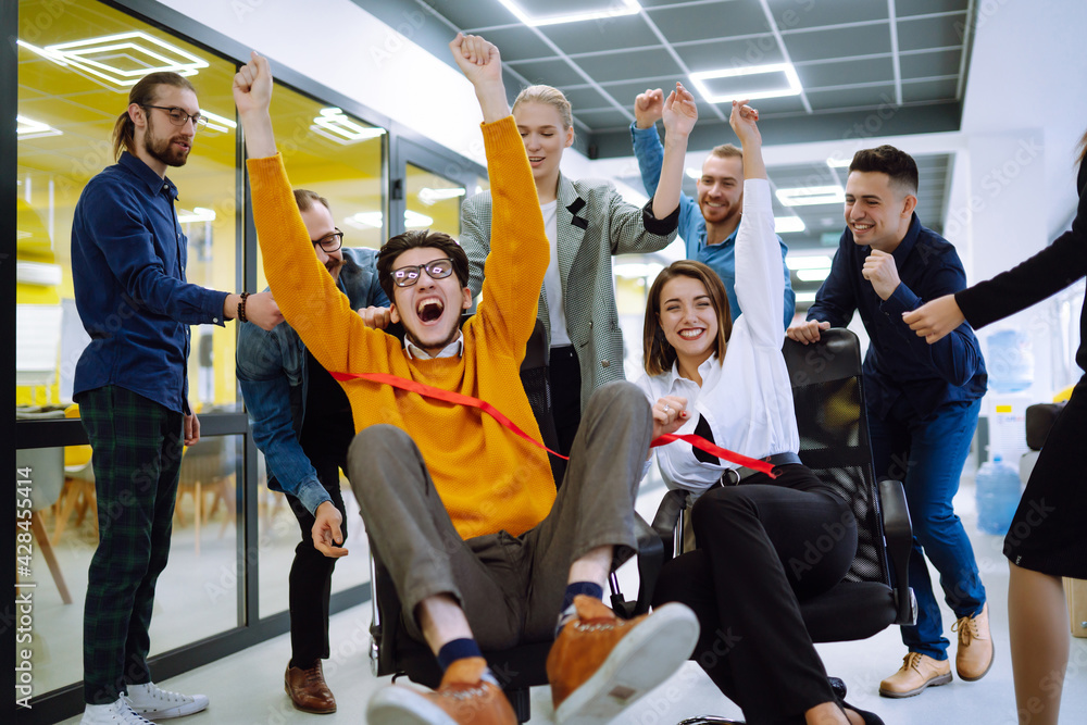 Friendly work team ride chairs in office room cheerfully excited ...