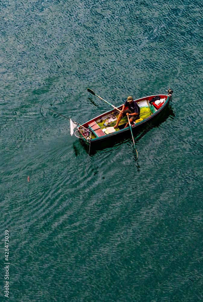 Fisherman Rows Small Wooden Boat While Catching Fish With Fishing Rods ...