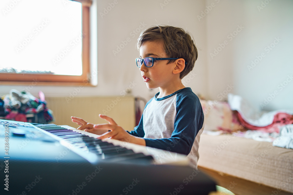 Small caucasian boy playing electric piano making music at home leisure ...