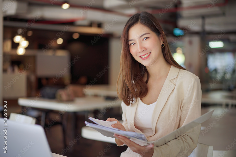 Beautiful asian secretary woman is checking notes in documentation ...