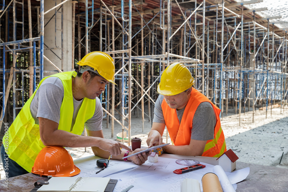 Engineer discussing with foreman about project in building construction ...