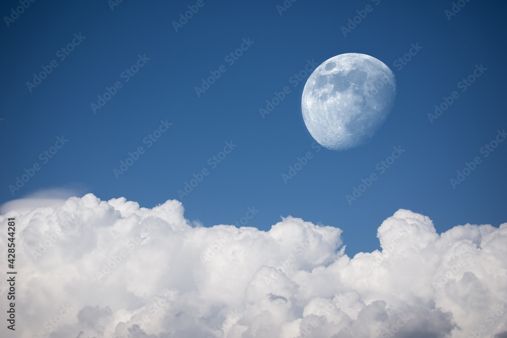 Low angle view of the moon in the waning gibbous phase on a blue cloudy ...