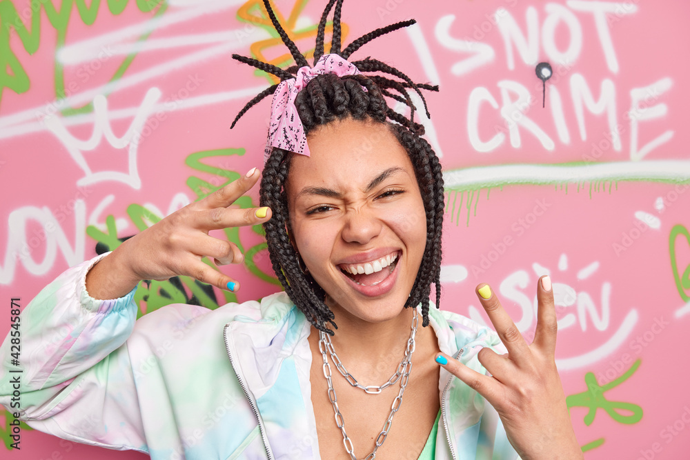 Cool hipster girl makes rap gesture feels crazy and happy smiles ...