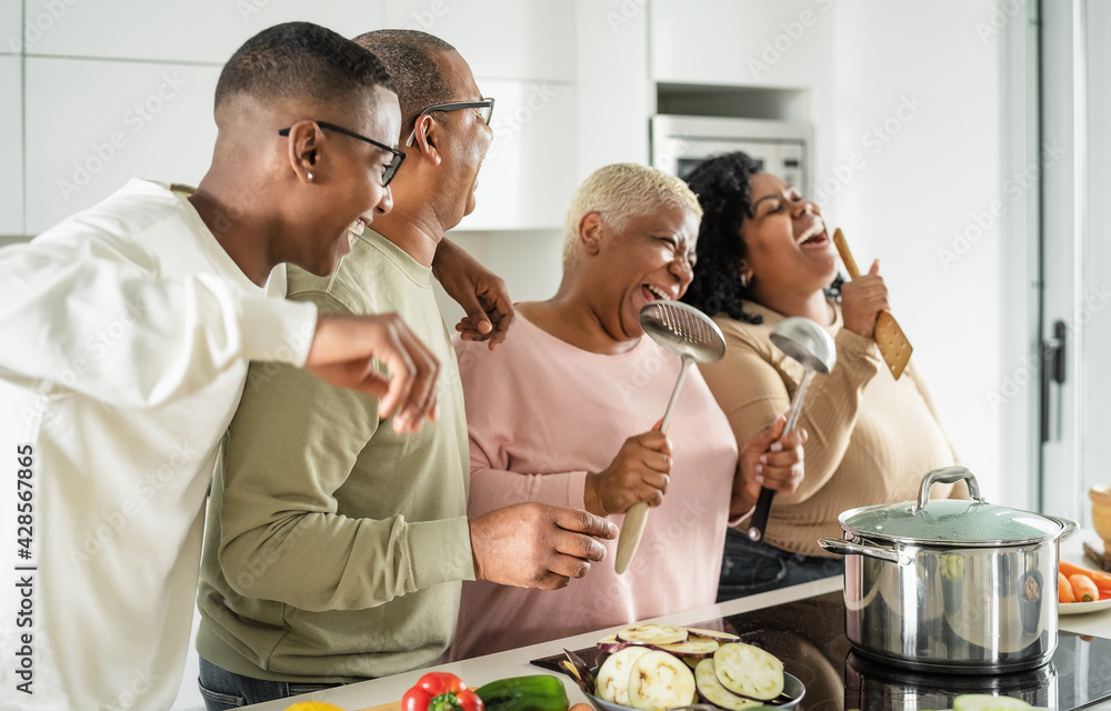 Happy African family having fun cooking together in modern kitchen ...