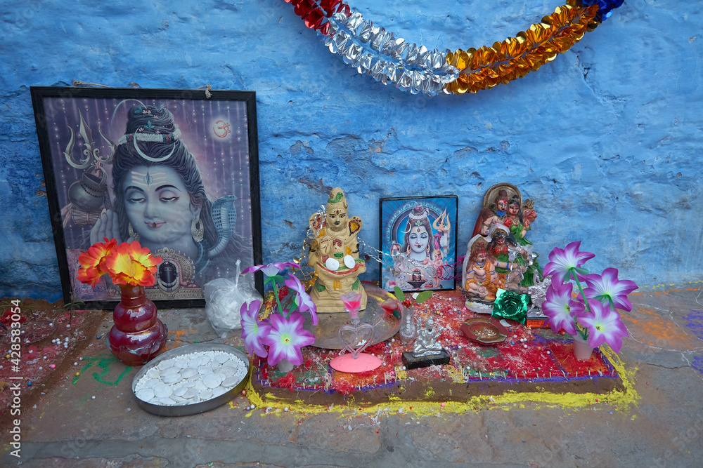 Indian gods figures are arranged in front of a wall. There are many ...