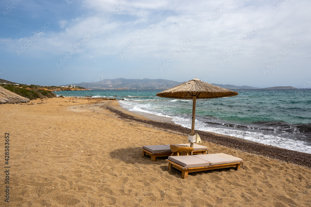 Sun beds and umbrellas at Soros beach on Antiparos Island. A wonderful ...