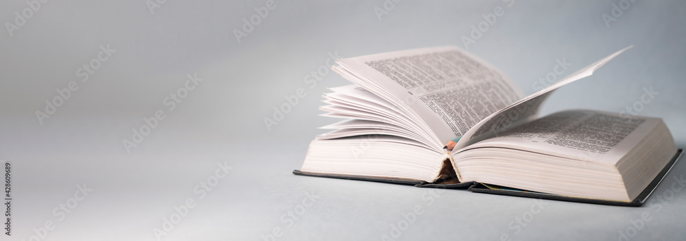 Open book with turning pages. Textbook in hard cover on table ...