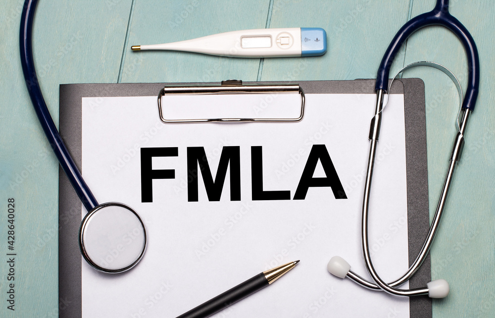 On a light blue wooden background, there is a paper labeled FMLA, a ...