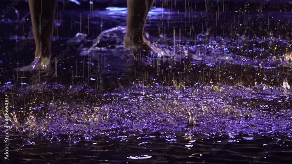 Contemporary dance ballerina dances sensually in rain on water surface ...