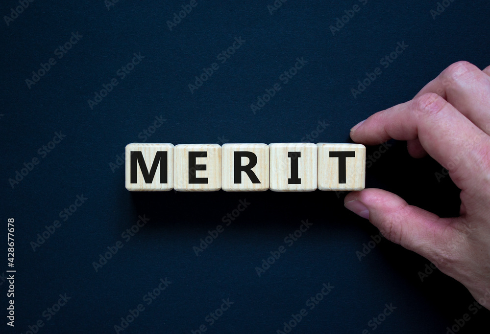 Merit symbol. Wooden cubes with the word 'merit'. Businessman hand ...