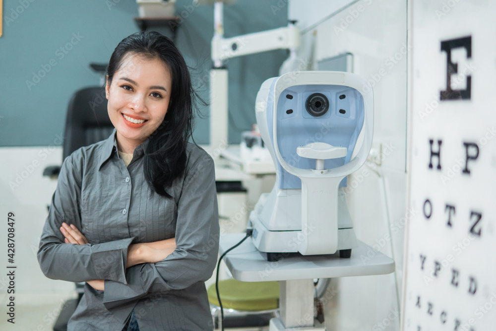 a female doctor posing next to an eye test kit located in an ...