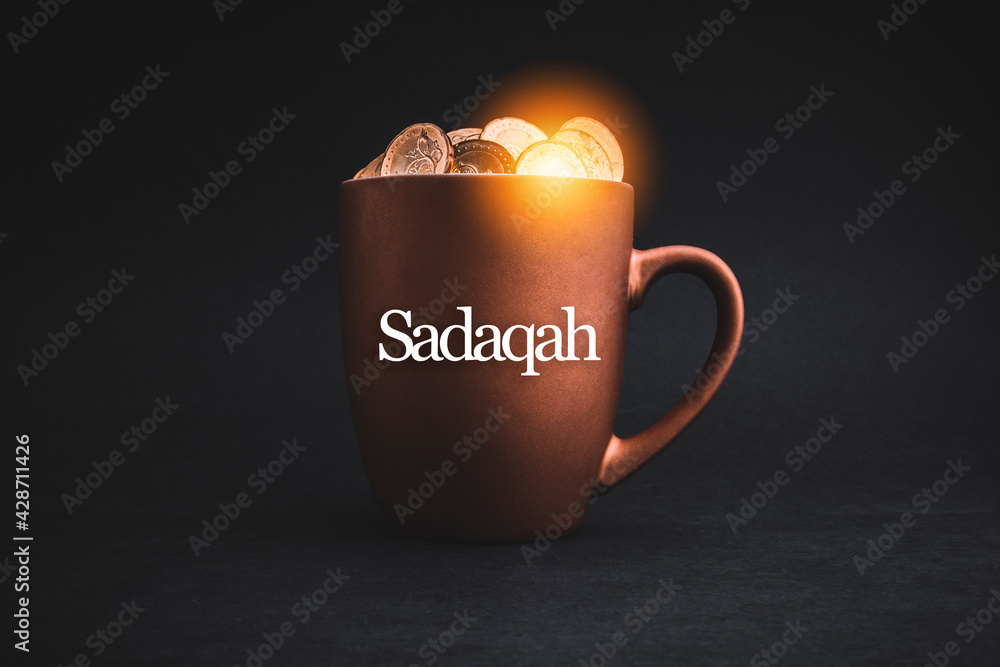 SADAQAH or Charity Gift text with Coins in cups on black background ...