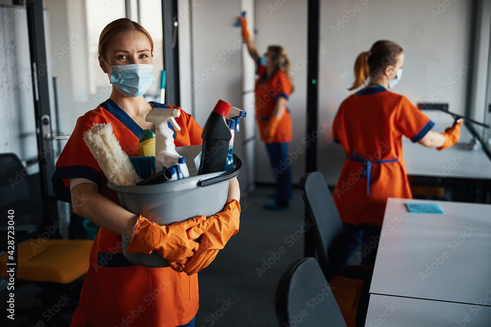 Female janitor with cleaning products standing among her busy ...