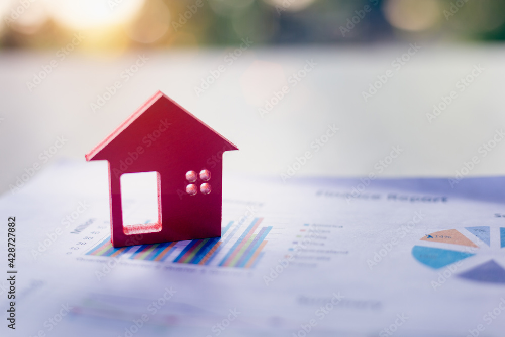 The red wooden house is placed on the graph or business information ...