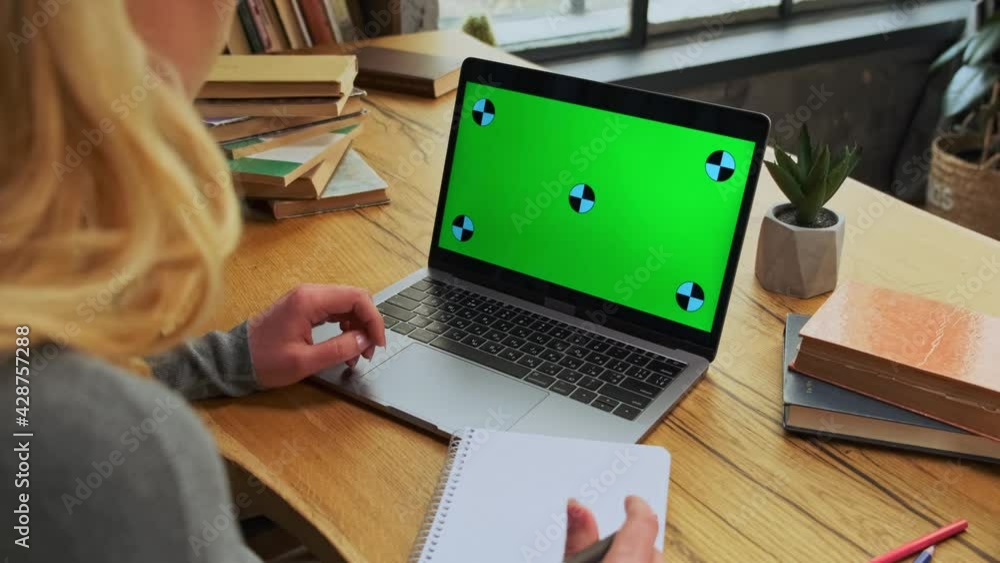 Young girl student studying, looking on green screen of laptop and ...