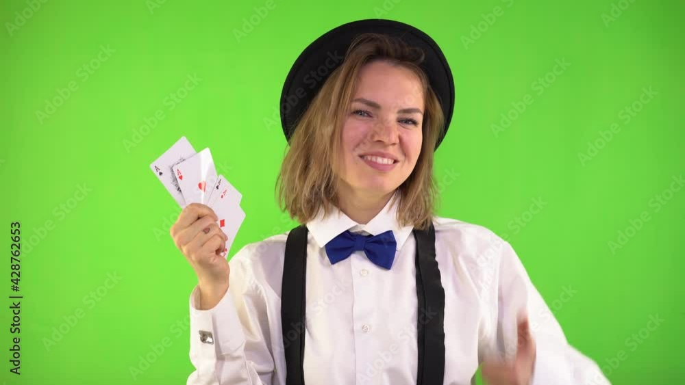 Croupier girl in a white shirt and hat and bow-tie shows playing cards ...