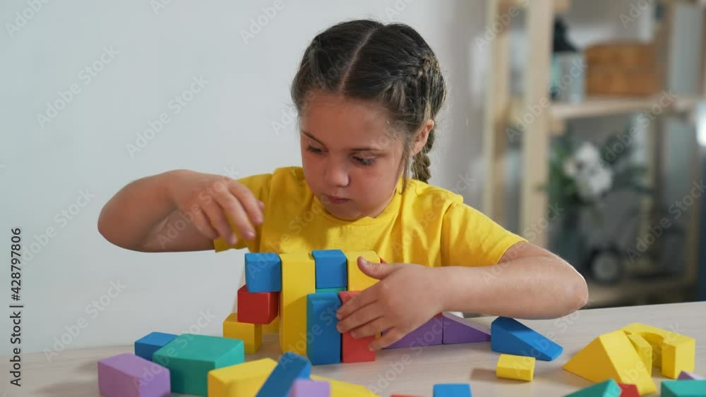 Kid is building house from constructor. Preschool girl plays at table ...