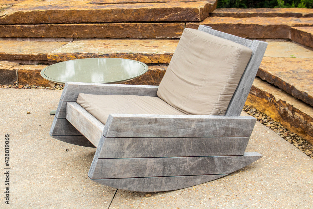 Modern wooden outdoor rocking chiar with cushions beside table on ...