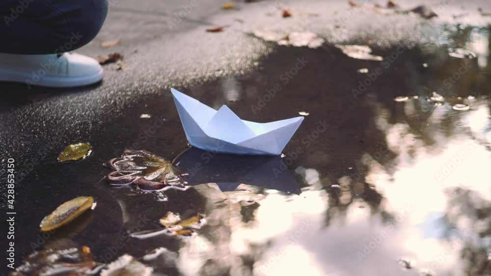 Child puts a paper boat into the water. Kid playing with paper boat ...
