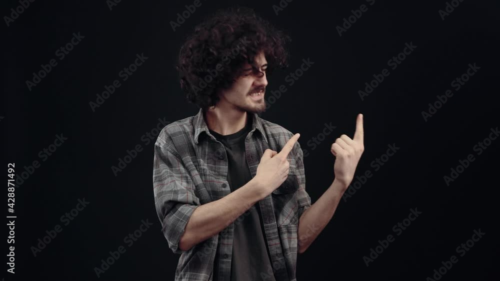Charismatic young man surprised, points with his index fingers to one ... Charismatic young man surprised, points with his index fingers to one ...