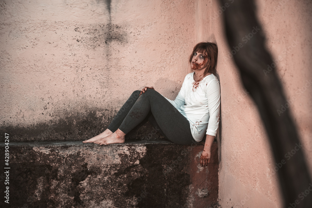 A squatting in front of a dirty wall, desperate, crying and wound girl ...