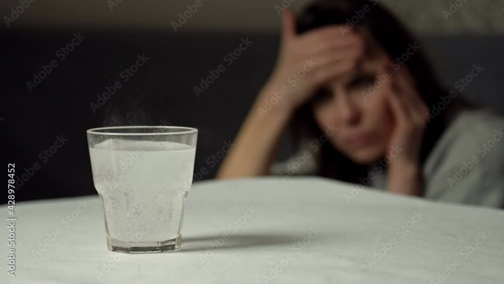 Glass of water with a dissolving tablet. Close-up. In the background, a ...