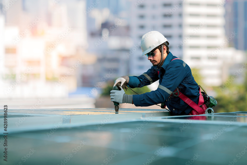 A worker wearing fall protection safety equipment while installing the ...