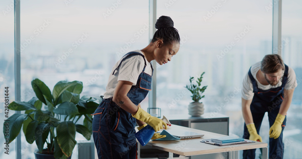 Indoor portrait of afro-americna pretty young woman janitor tidying ...