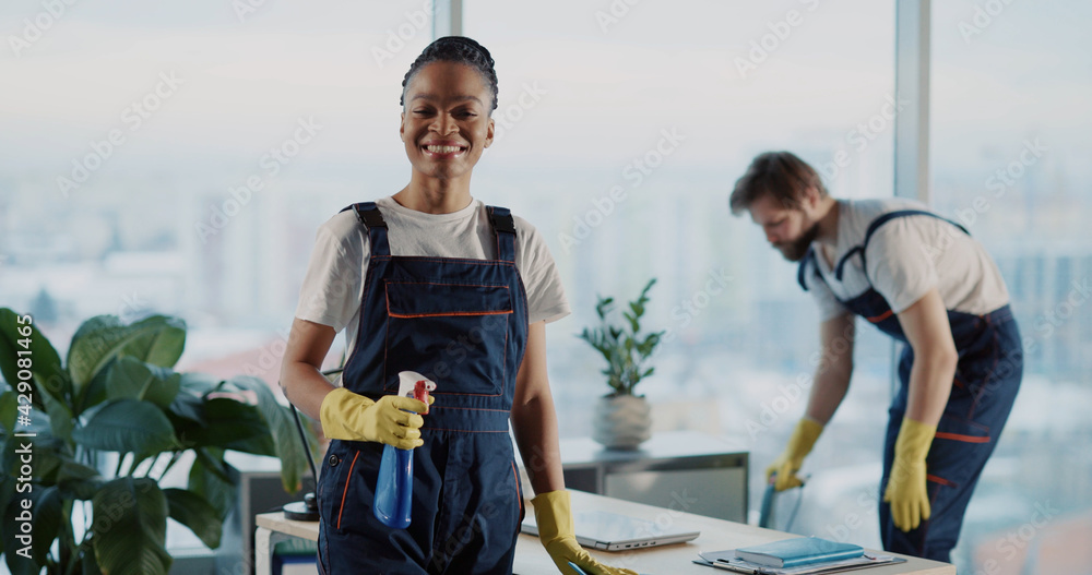 Indoor portrait of afro-americna pretty young woman janitor tidying ...