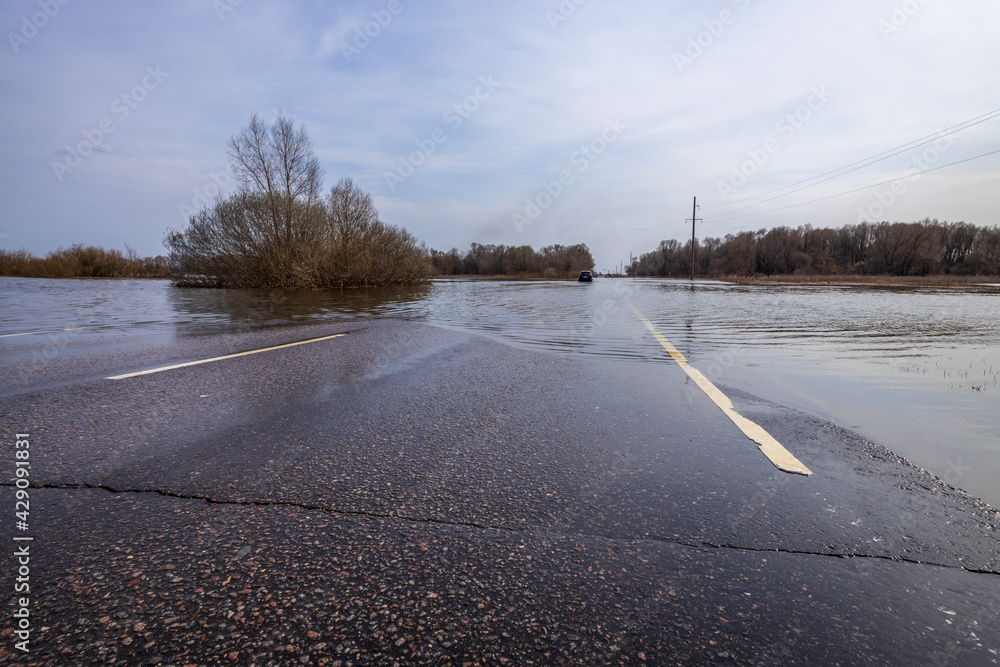 The road is under water due to flooding..Asphalted road between forest ...