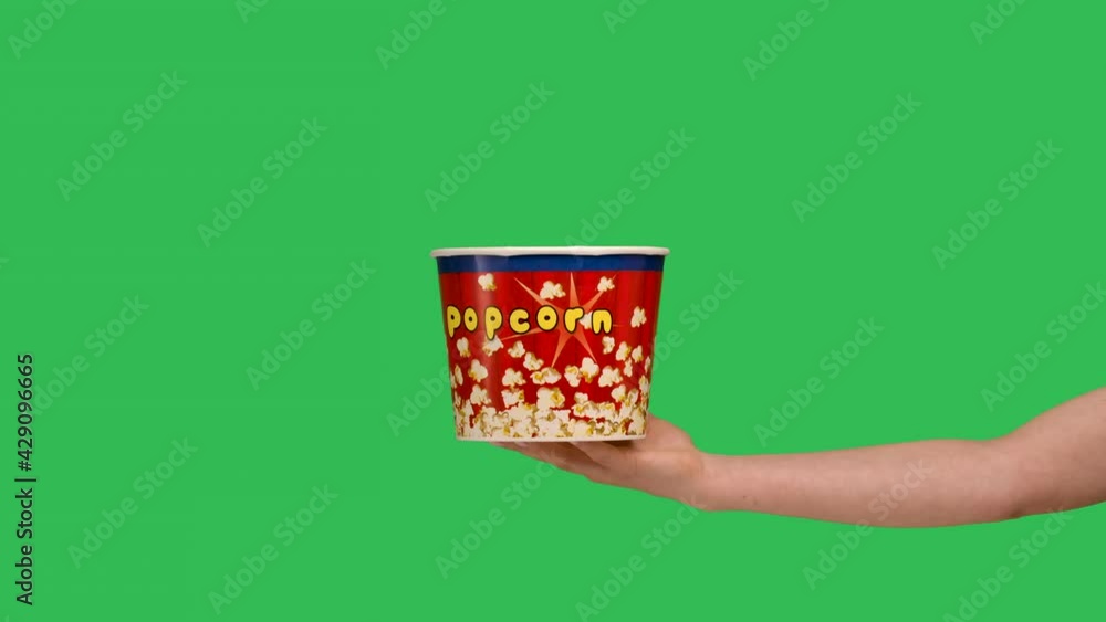 Female hands giving a bucket of popcorn close up. Woman points to the ...