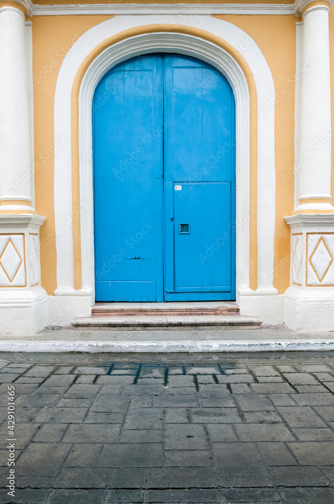 Close up of very large, tall arched bright blue wooden double doors ...