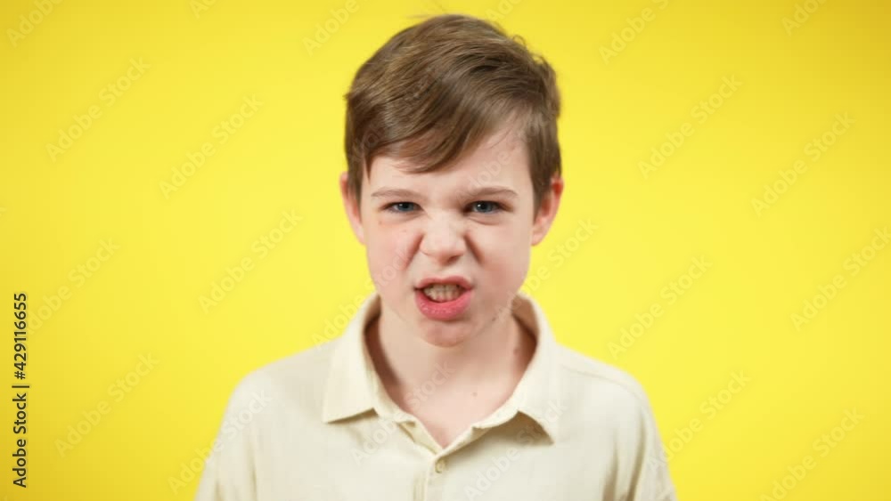 Close-up of angry little boy making furious facial expression at yellow ...