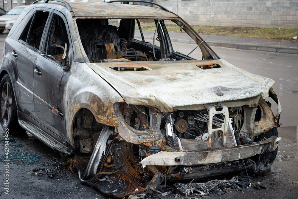 A car after a fire, close-up. A blown-up and burnt-out SUV on a city ...