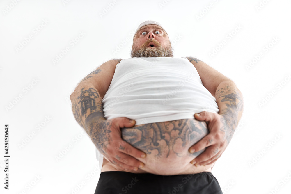 fat man with big belly and tattoes in sports wear is holding his ...