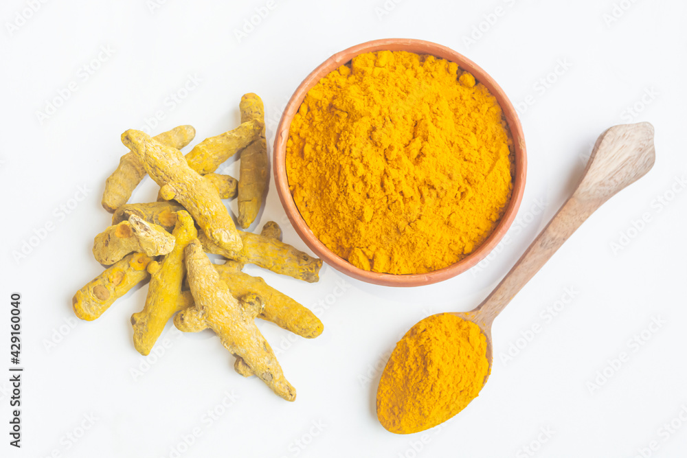 Dry turmeric or haldi powder in a earthen bowl with turmeric roots on ...