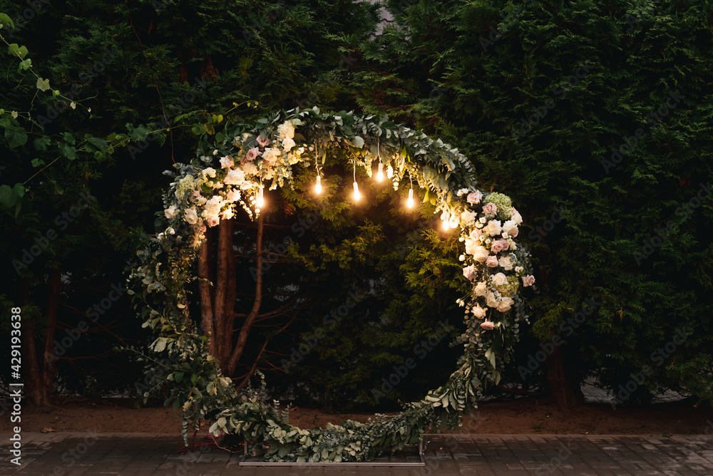Beautiful wedding arch with retro lights decorated with night flowers ...