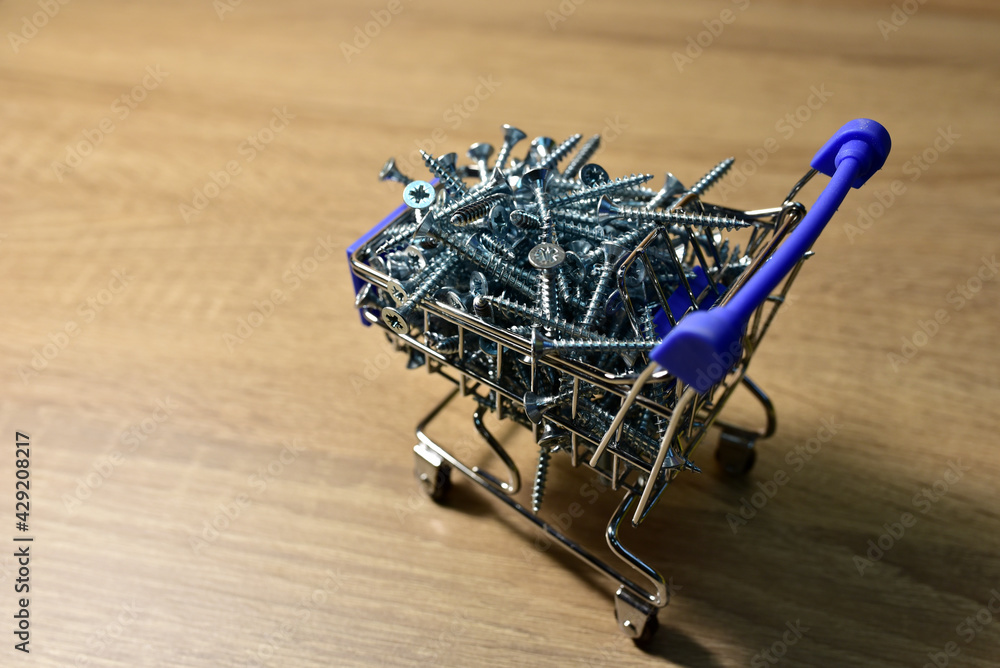 Self-tapping screws in a shopping cart on wooden a table. Screw for ...