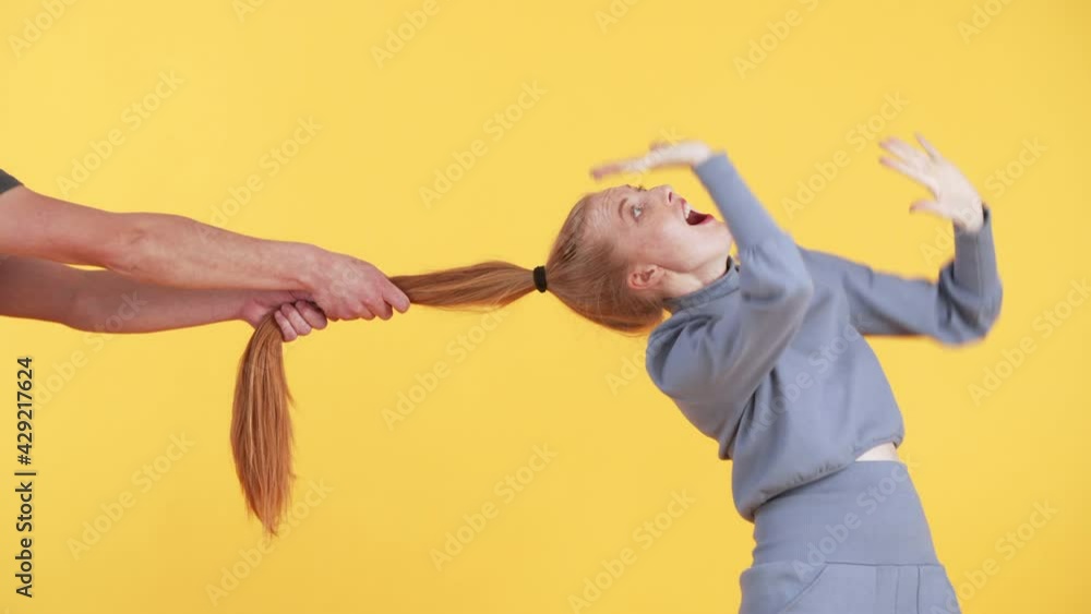 Male hands are pulling girl's ponytail. Young woman with freckles is ...